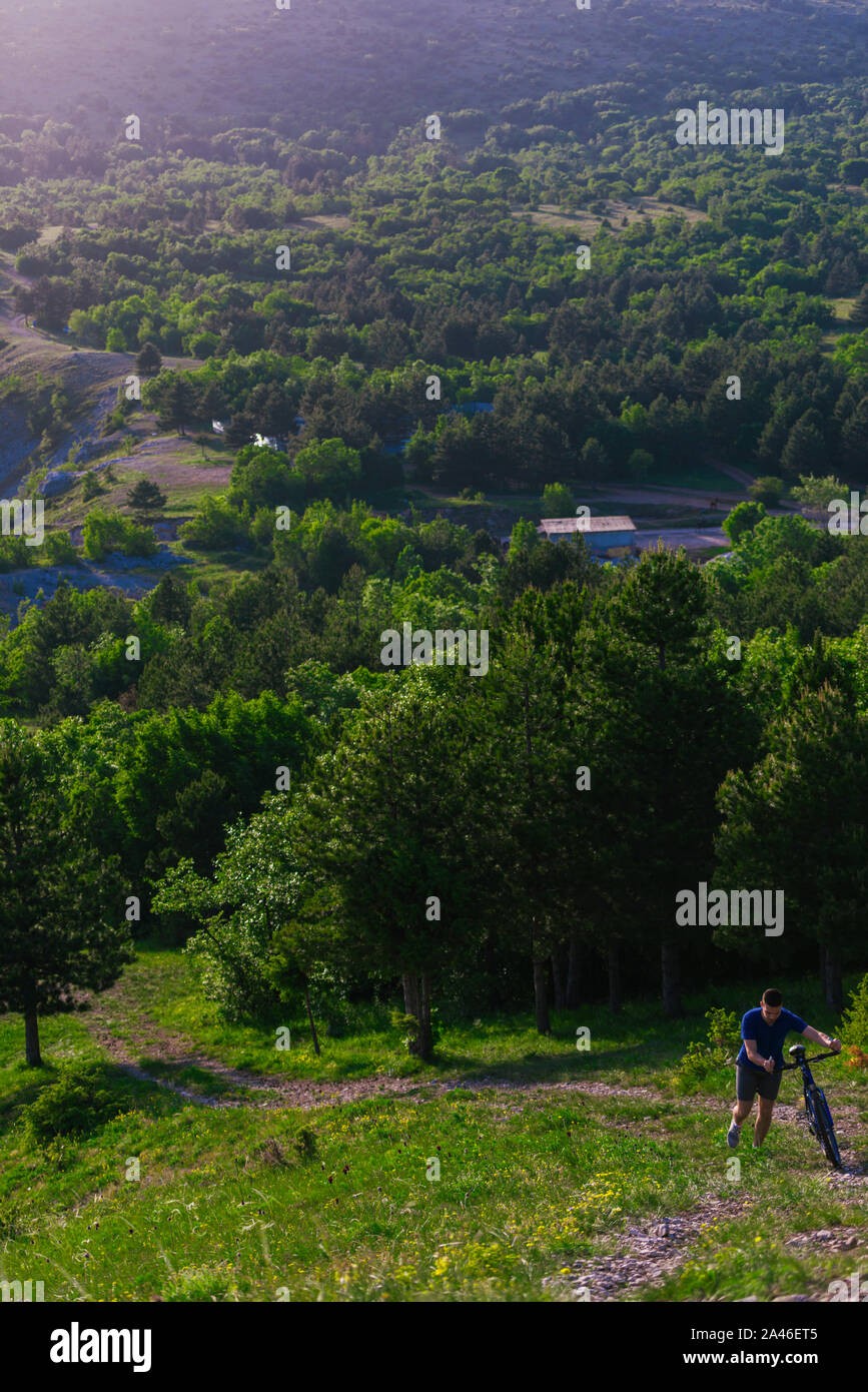 Perspective of a fit mountain biker pushing his bike uphill with ...