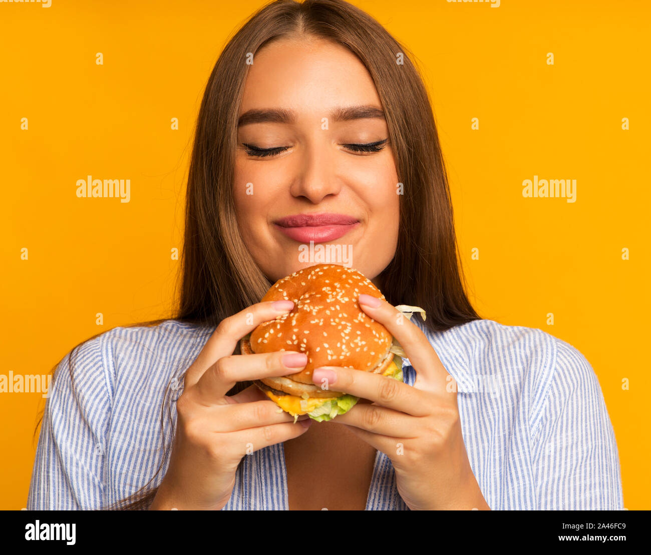 Happy Girl Eating Burger Standing, Studio Shot Stock Photo - Alamy