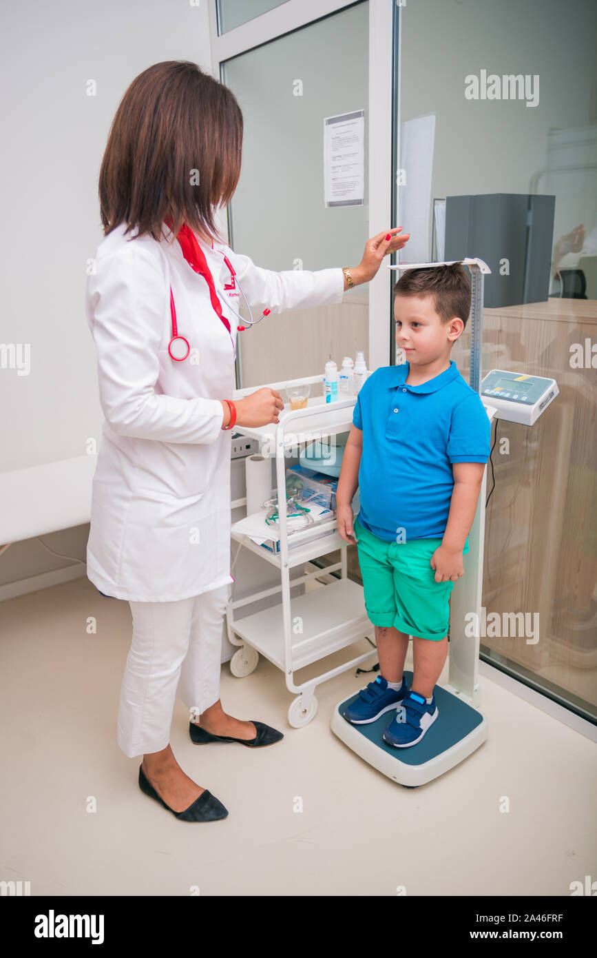 Female doctor measuring the height of little boy in a clinic ( hospital ...