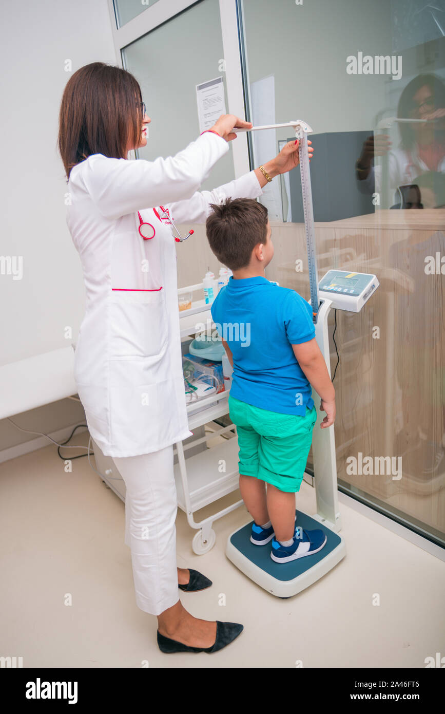 Female doctor measuring the height of little boy in a clinic ( hospital ...