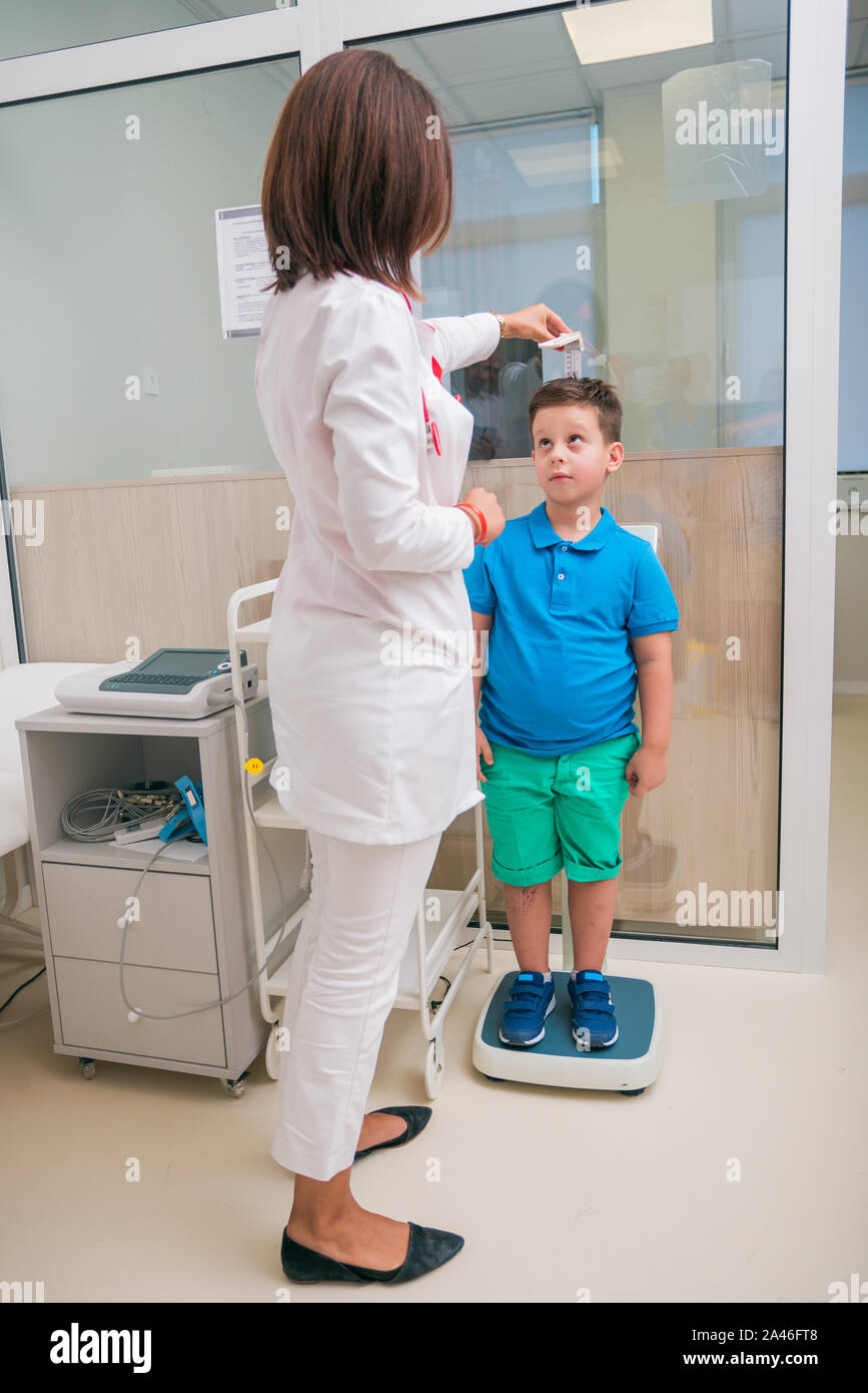 Female doctor measuring the height of little boy in a clinic ( hospital ...