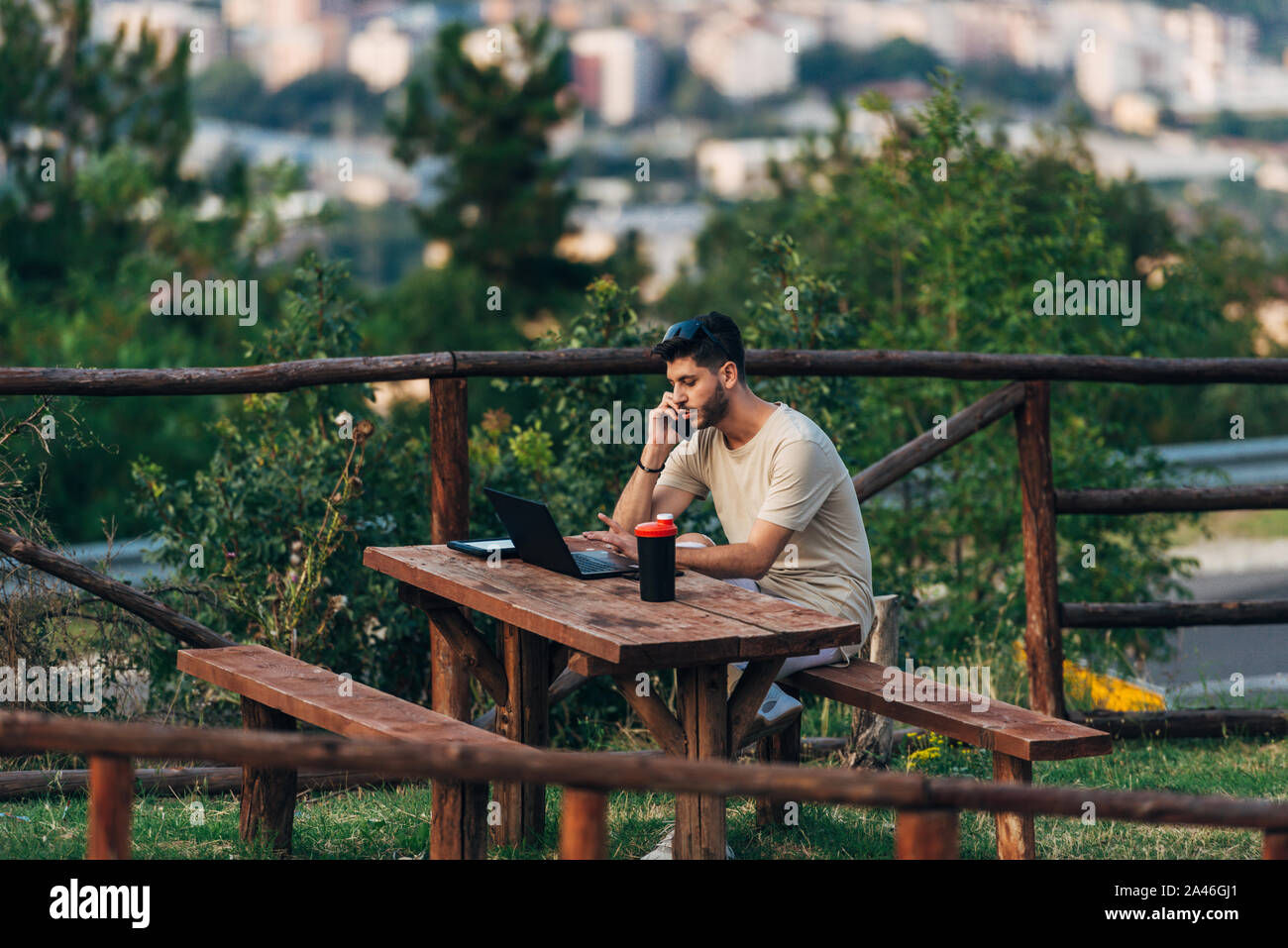 Concentrate man sitting by the table with laptop computer and mobile on ...