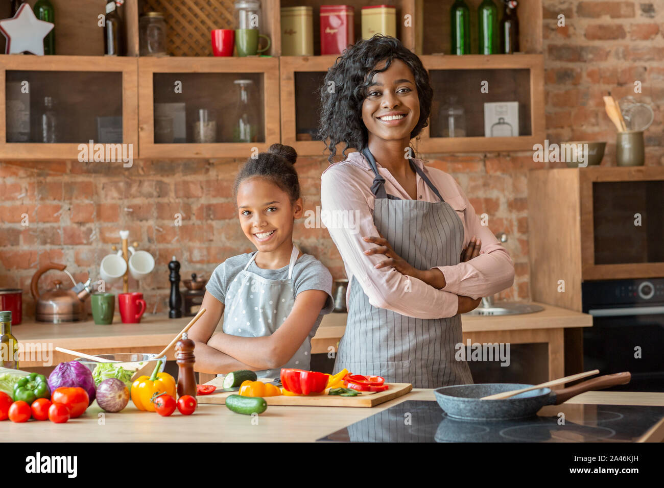 Confident mom and daughter posing on camera while cooking Stock Photo ...