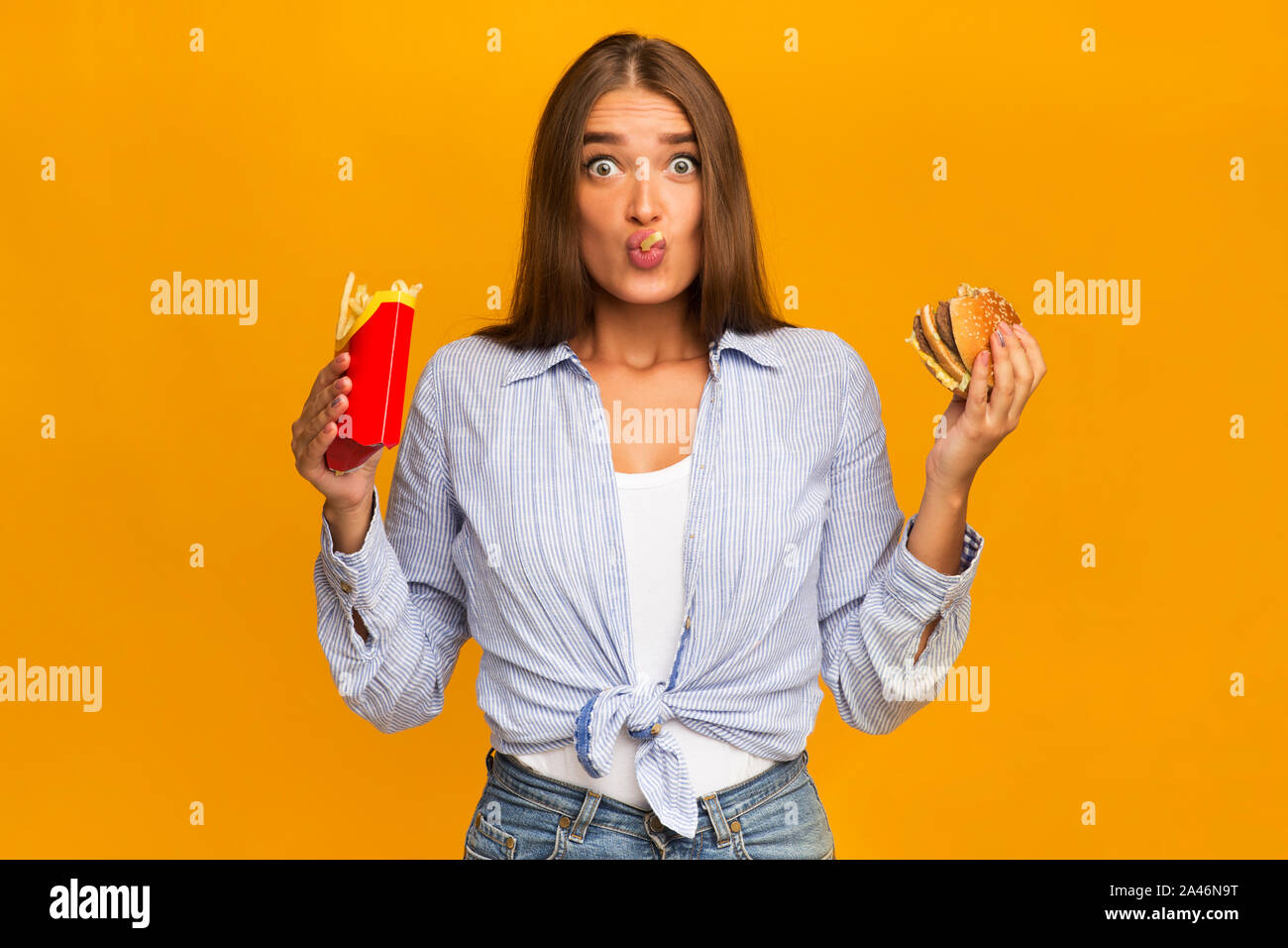 Surprised Woman Eating Burger And French Fries, Studio Shot Stock Photo ...