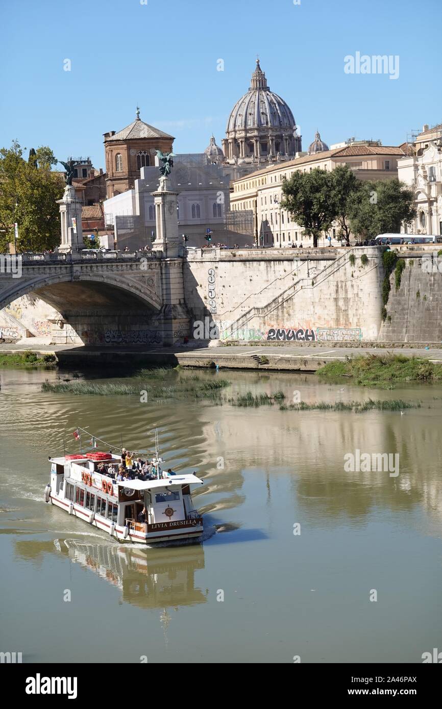 A pleasure boat on the River Tiber with the dome of St Peter's Basilica ...