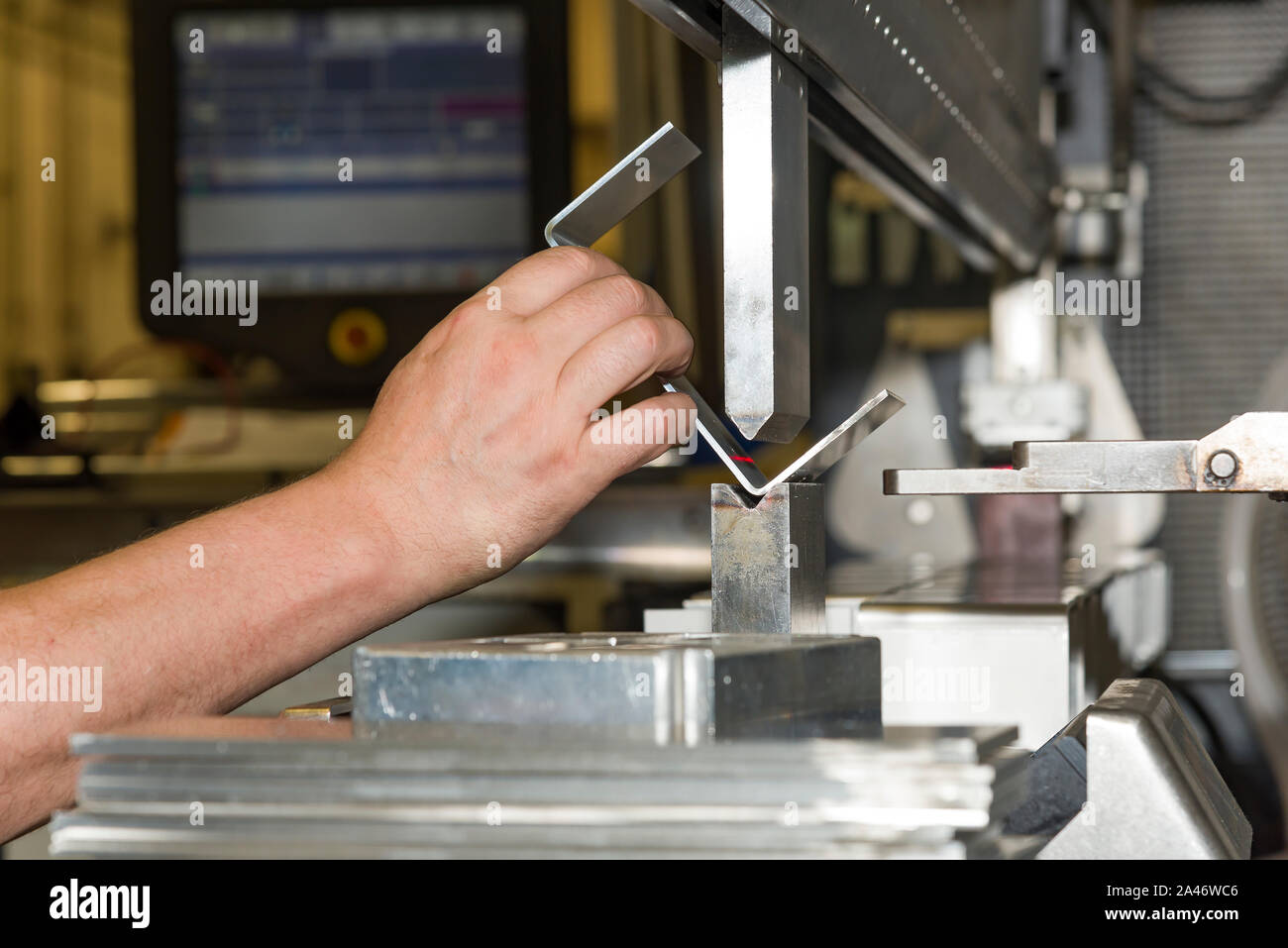 worker operating metal press machine at workshop. Bending of metal on ...