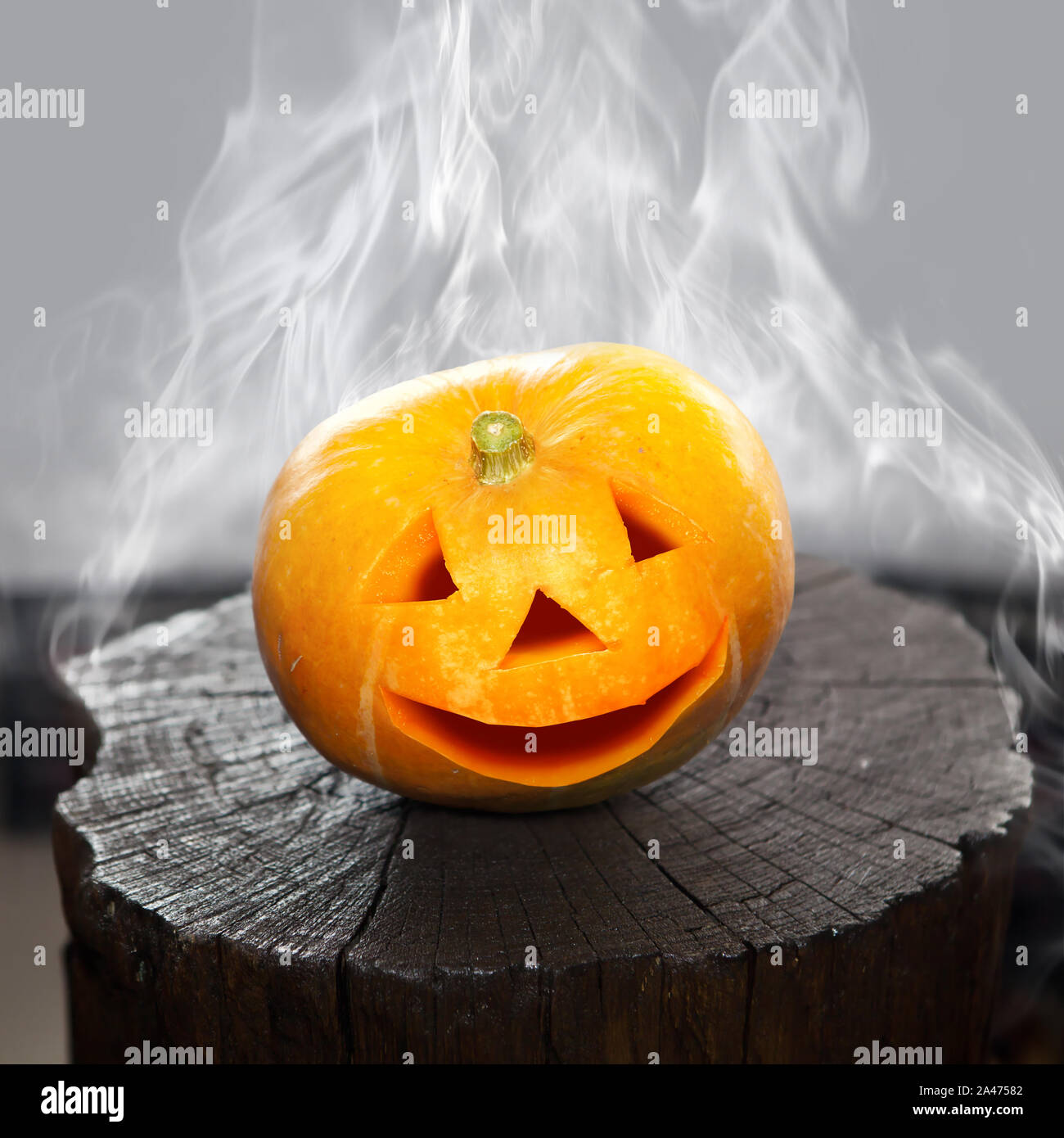 Pumpkin that laughs on a charred stub in smoke. Scenery for Halloween ...