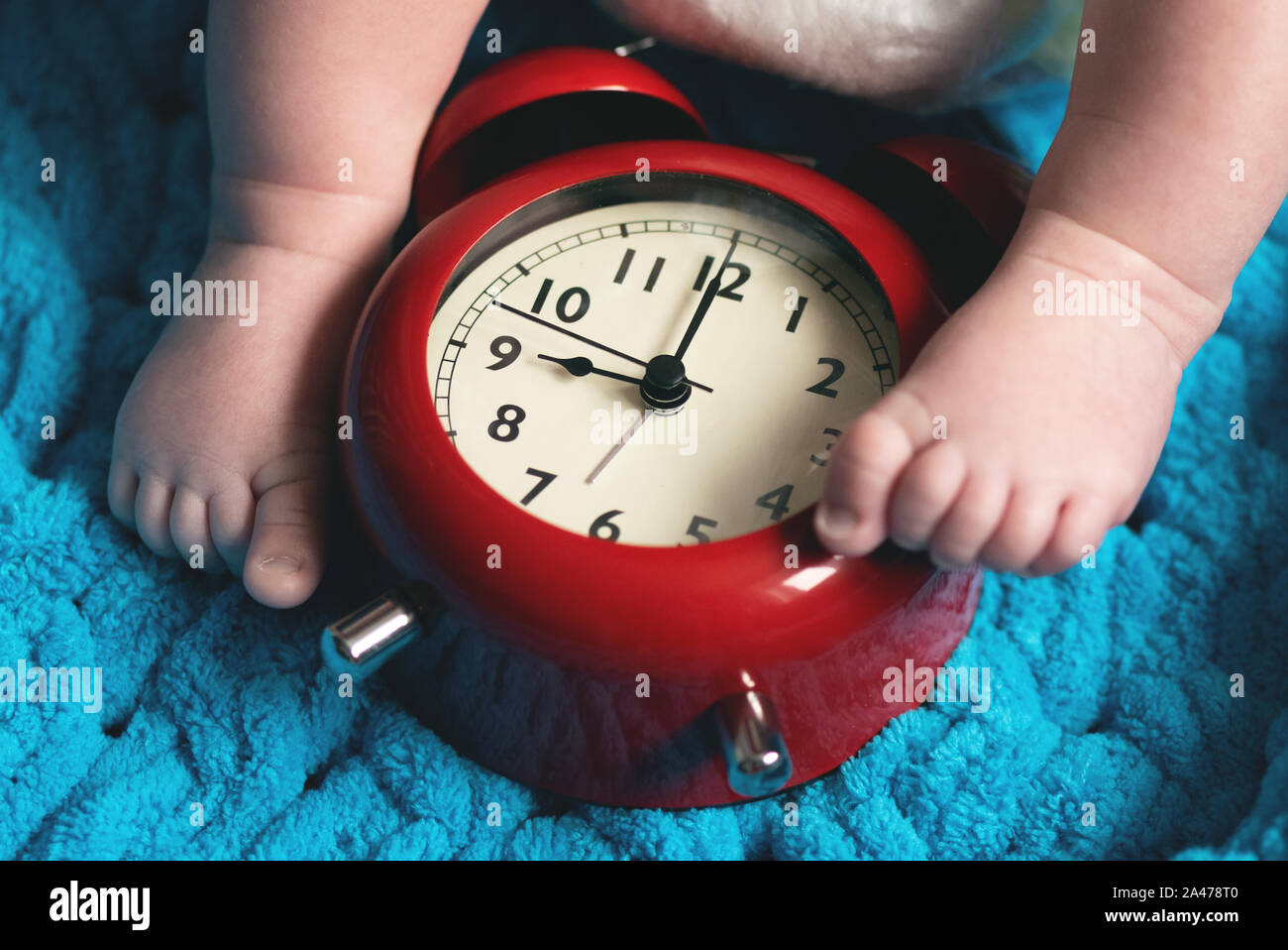 Baby feet and a red alarm clock on a blue towel background Stock Photo ...