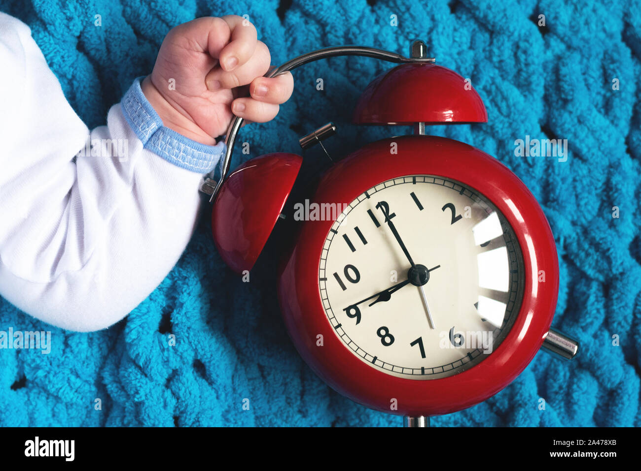Baby hand with a red alarm clock. Time to eat Stock Photo - Alamy