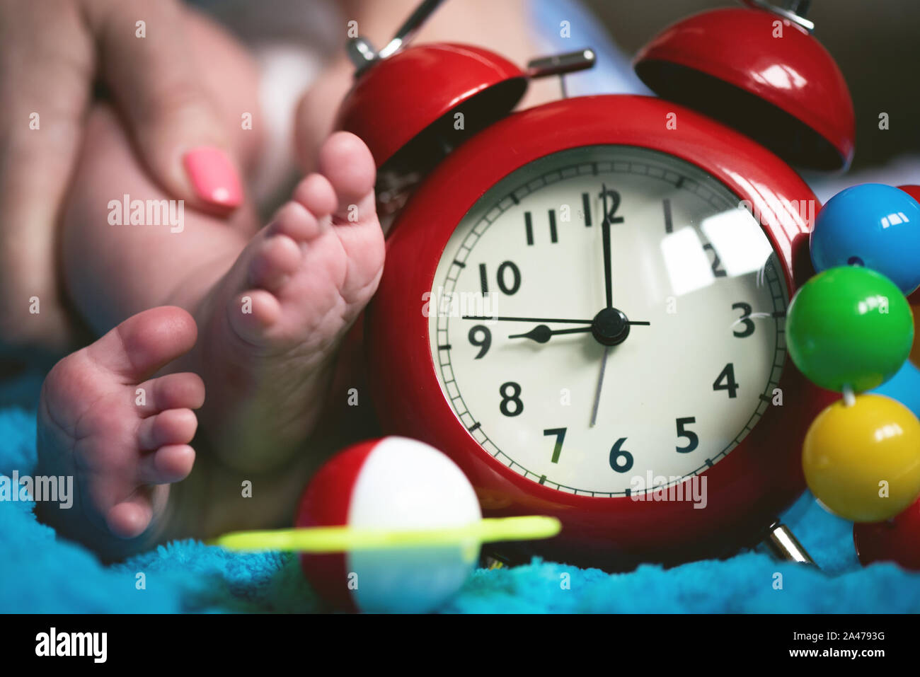Baby feet, mother hands and red alarm clock with a toys Stock Photo - Alamy