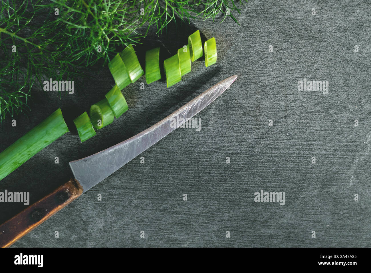 Onion and kitchen knife on a stone black cutting board background Stock ...