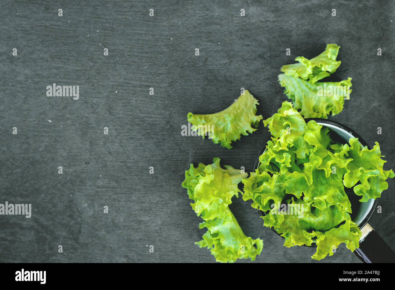 Green lettuce leaves in kitchen ladle on stone cutting board on kitchen ...