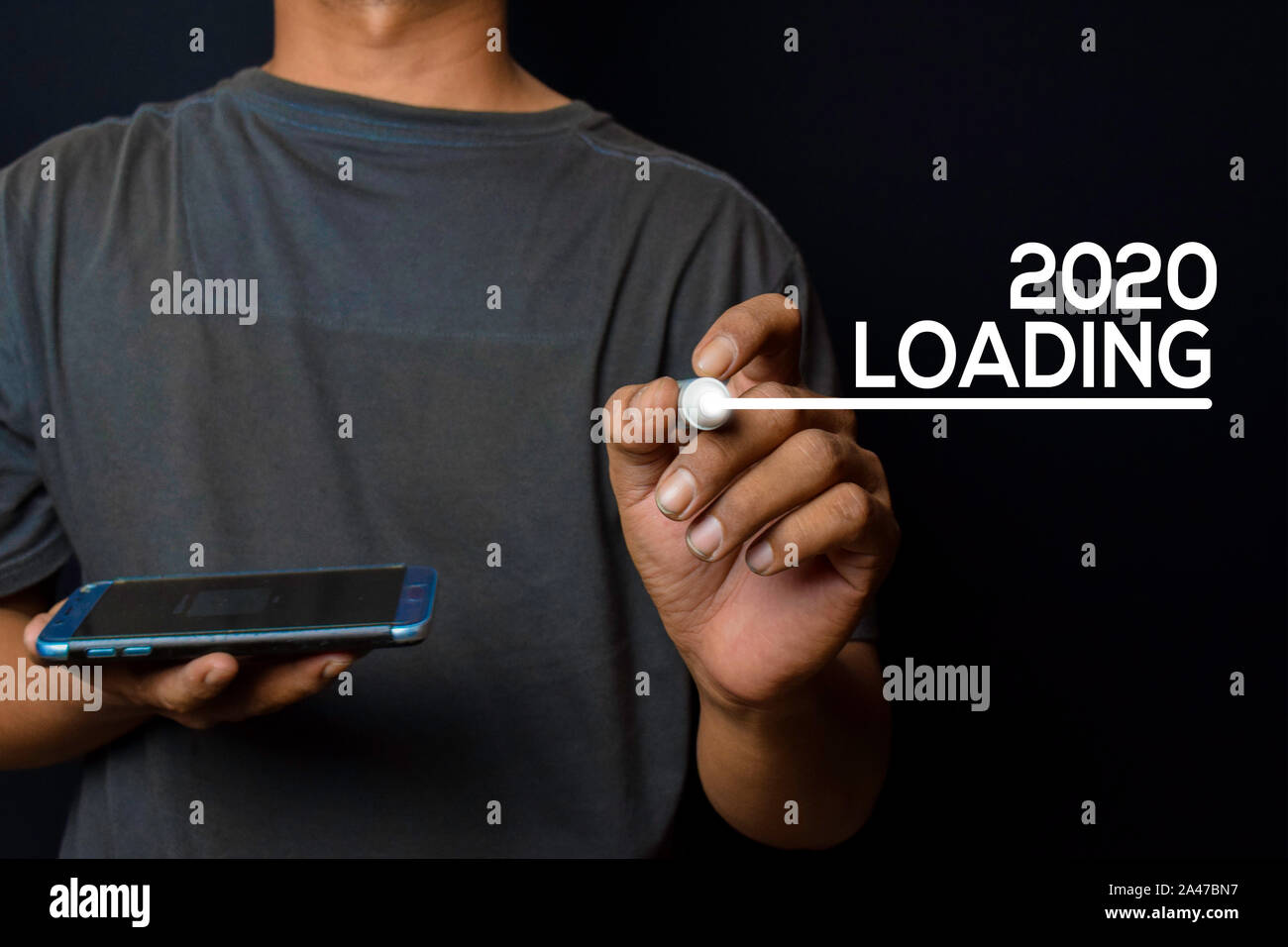 Young man write on 2020 Loading text with smartphone isolated on black ...