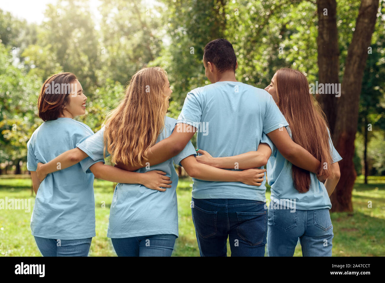 Volunteering. Young people volunteers outdoors walking hugging back ...
