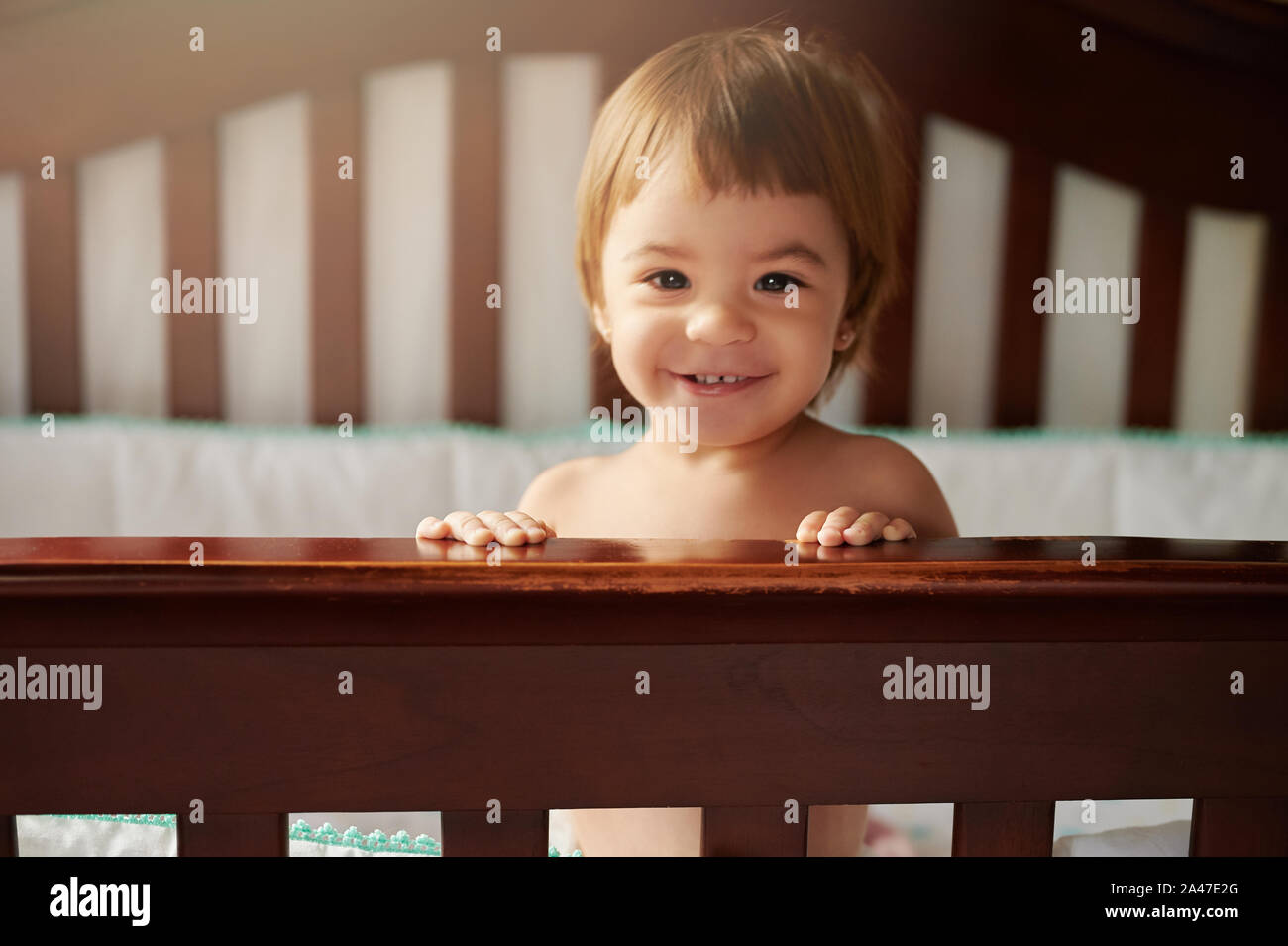 Happy smiling baby girl standing in crib bed after sleep Stock Photo ...