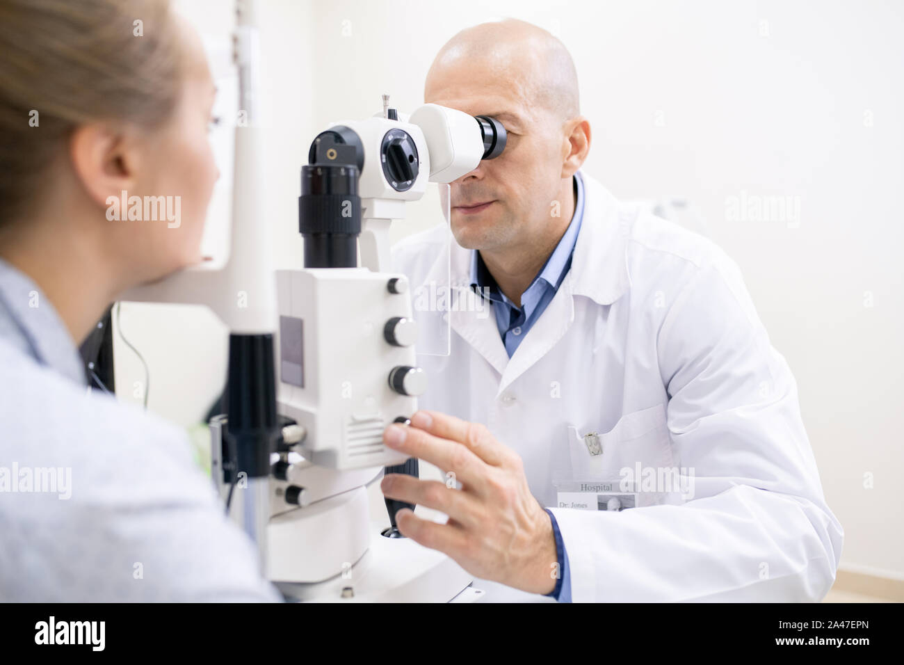 Middle aged professional optometrist checking eyesight of female ...
