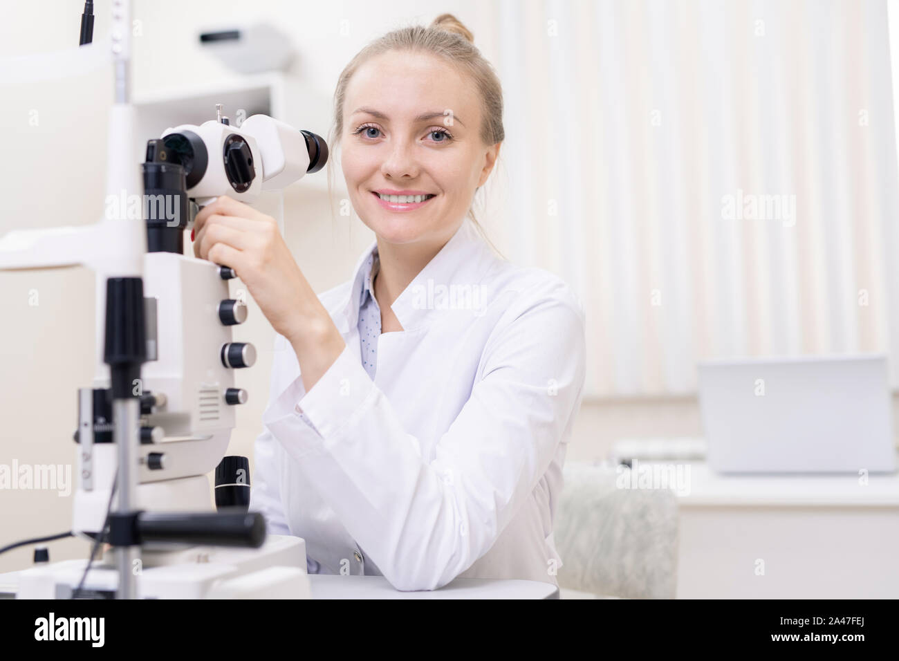 Happy young contemporary ophthalmologist with eye vision check-up ...