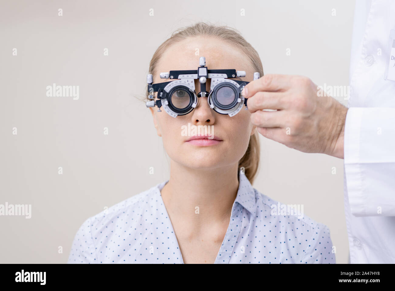 Young woman having her eye vision examined while looking through ...