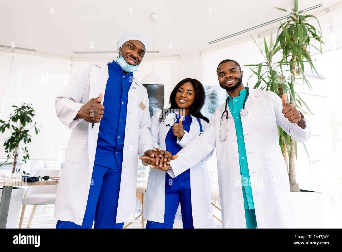 Doctors team. Health care. Three happy African doctors stack hands ...