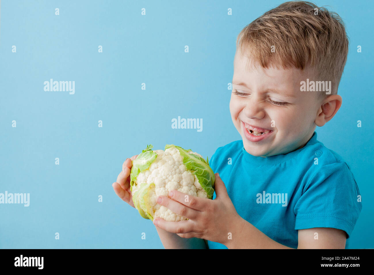 Little Boy Holding Broccoli in his hands on blue background, diet and ...