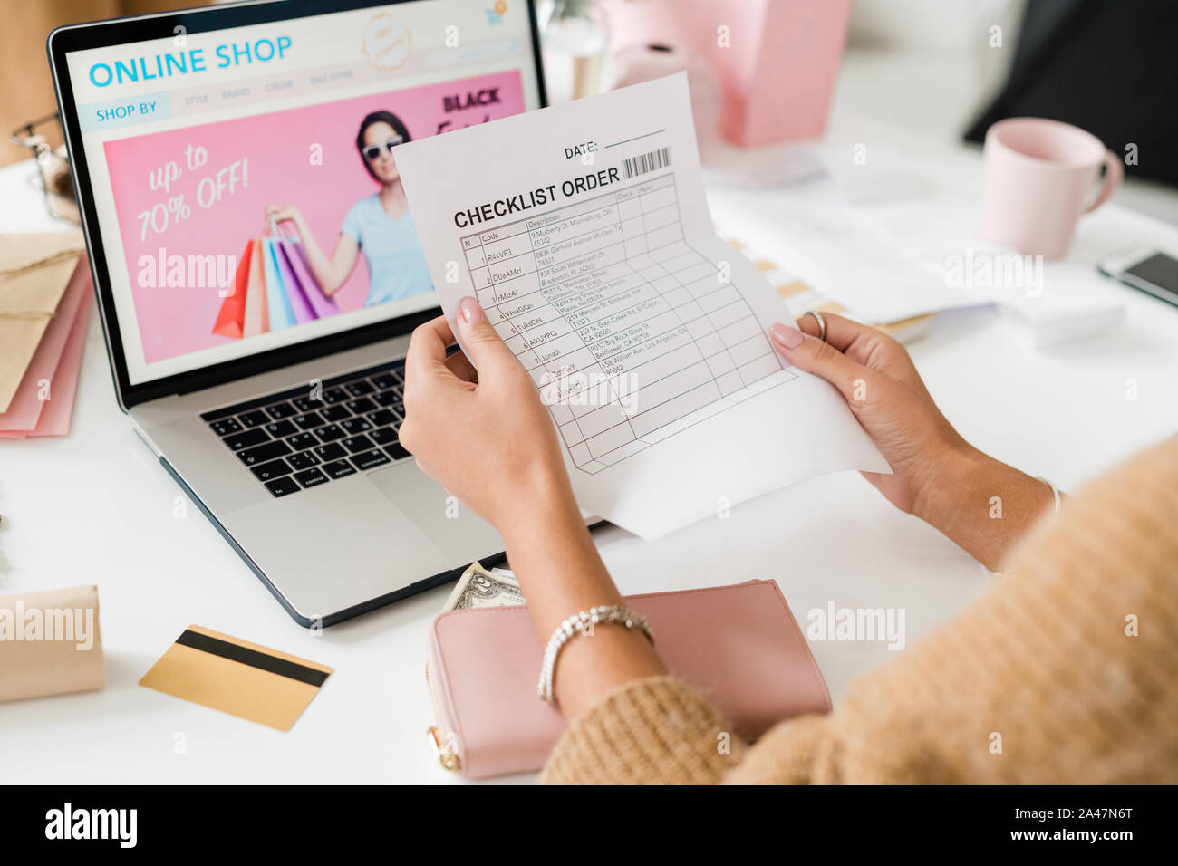 Young female customer holding and reading checklist paper over laptop ...