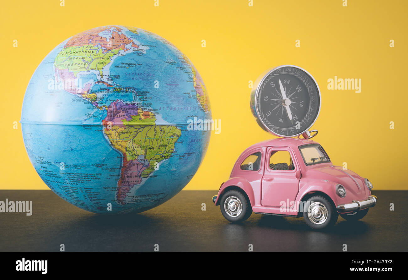 Pink retro car and compass with world globe sphere on yellow background ...
