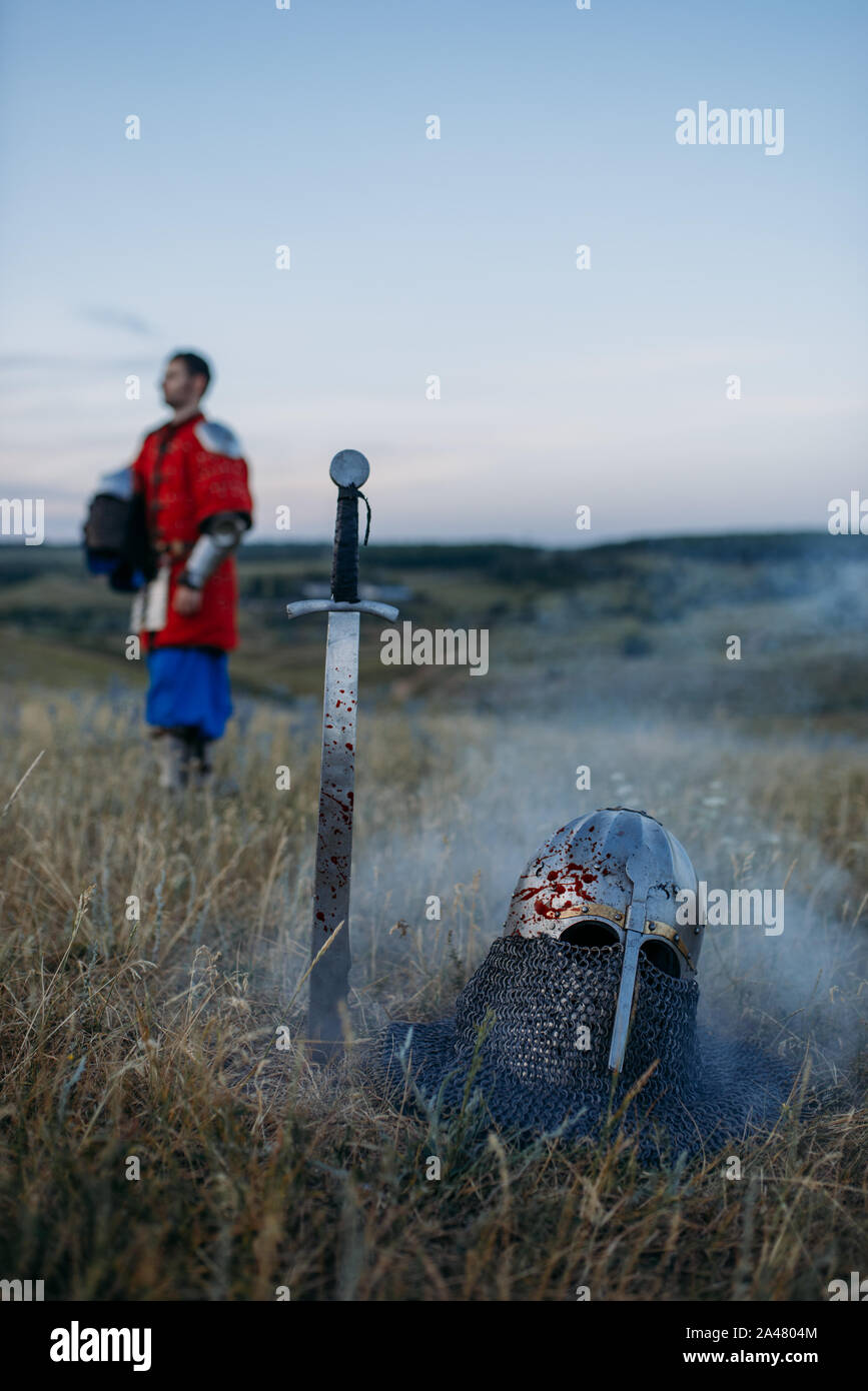 Sword stuck in the ground and metal knight helmet Stock Photo - Alamy