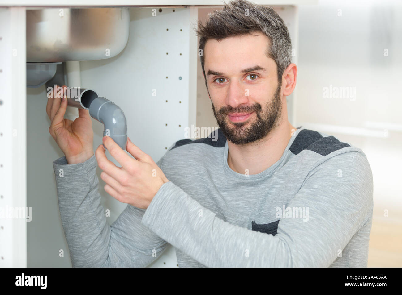 male plumber fixing pipe into the steel sink Stock Photo - Alamy