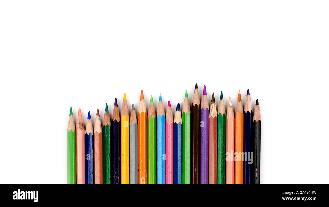 Old colored pencils. Some old colored pencils lined up on a white table ...