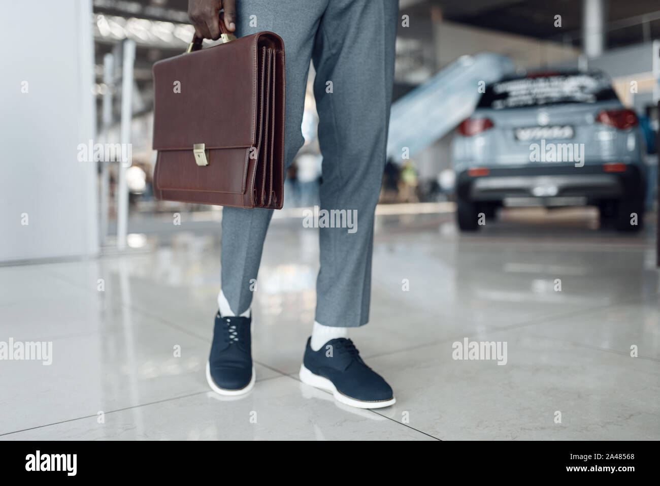 Businessman holds briefcase in car showroom Stock Photo - Alamy