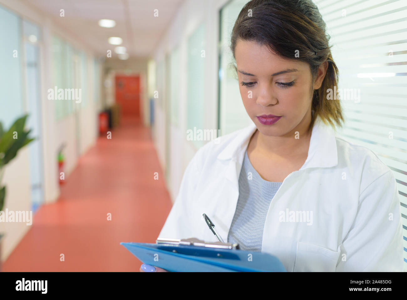 female nurse making notes on clipboard in hospital corridor Stock Photo ...