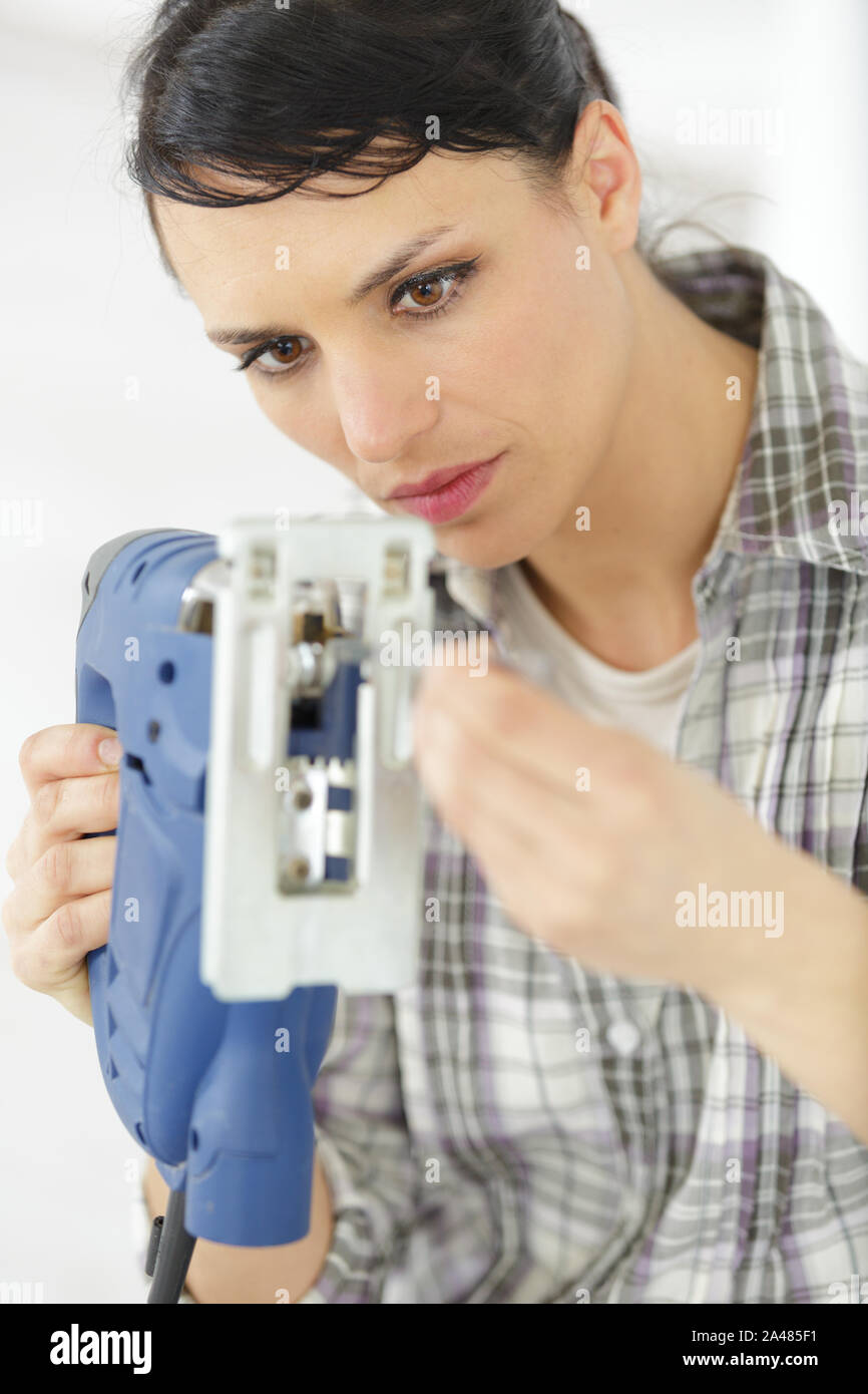 serious middle-aged professional female carpentry fixing an electric ...