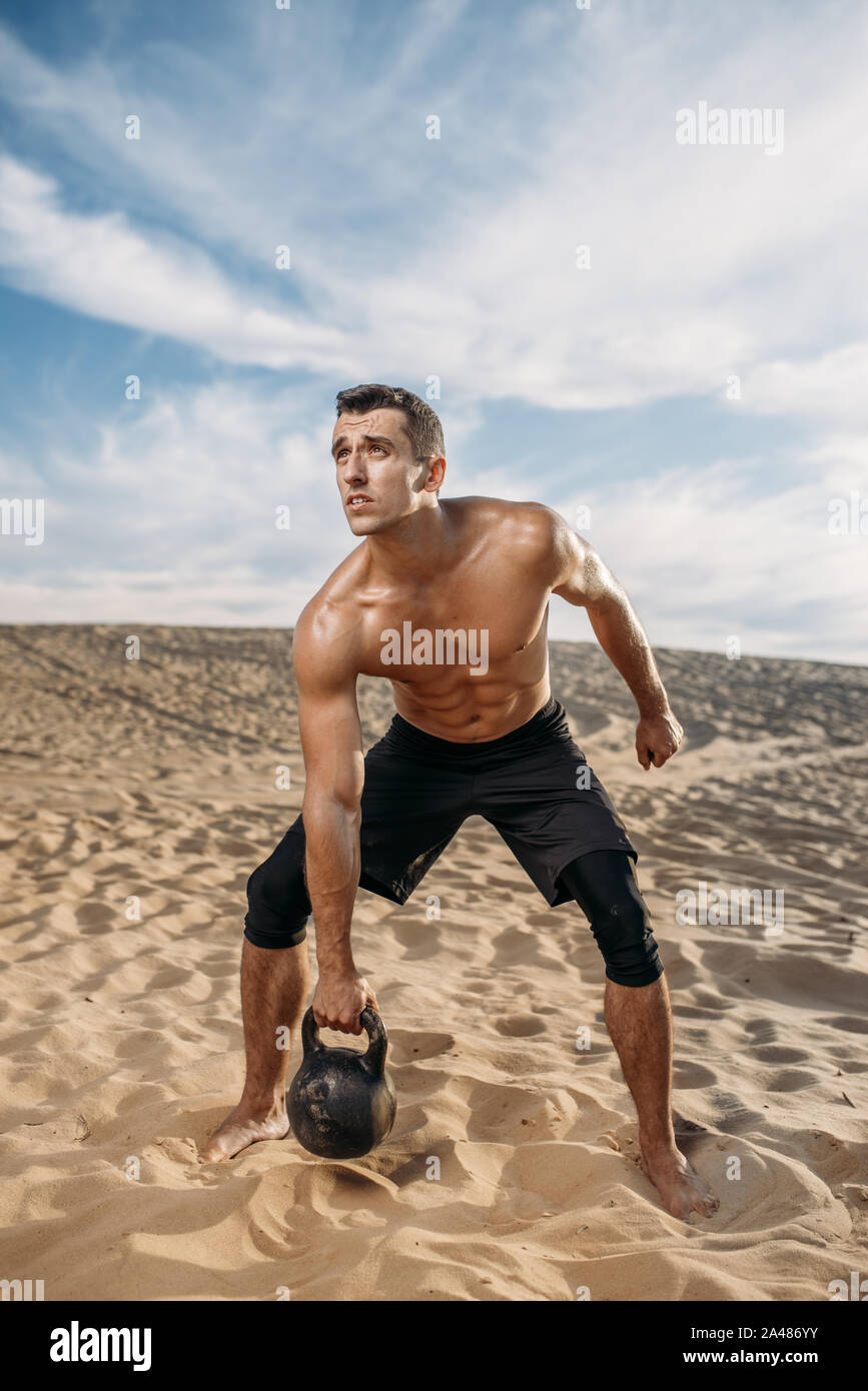Athlete doing exercise with kettlebell in desert Stock Photo - Alamy