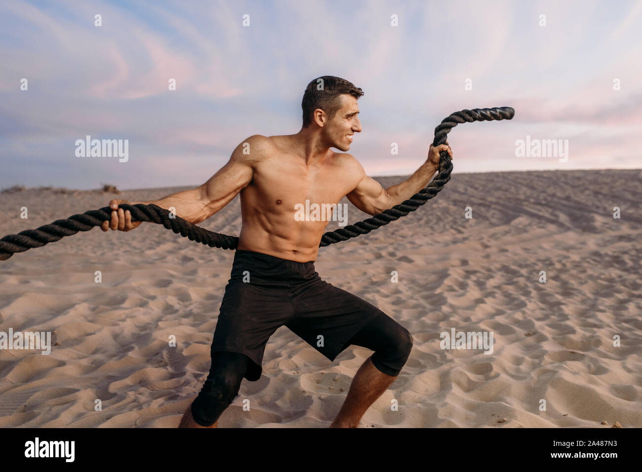 Muscular man doing exercise with rope in desert Stock Photo - Alamy