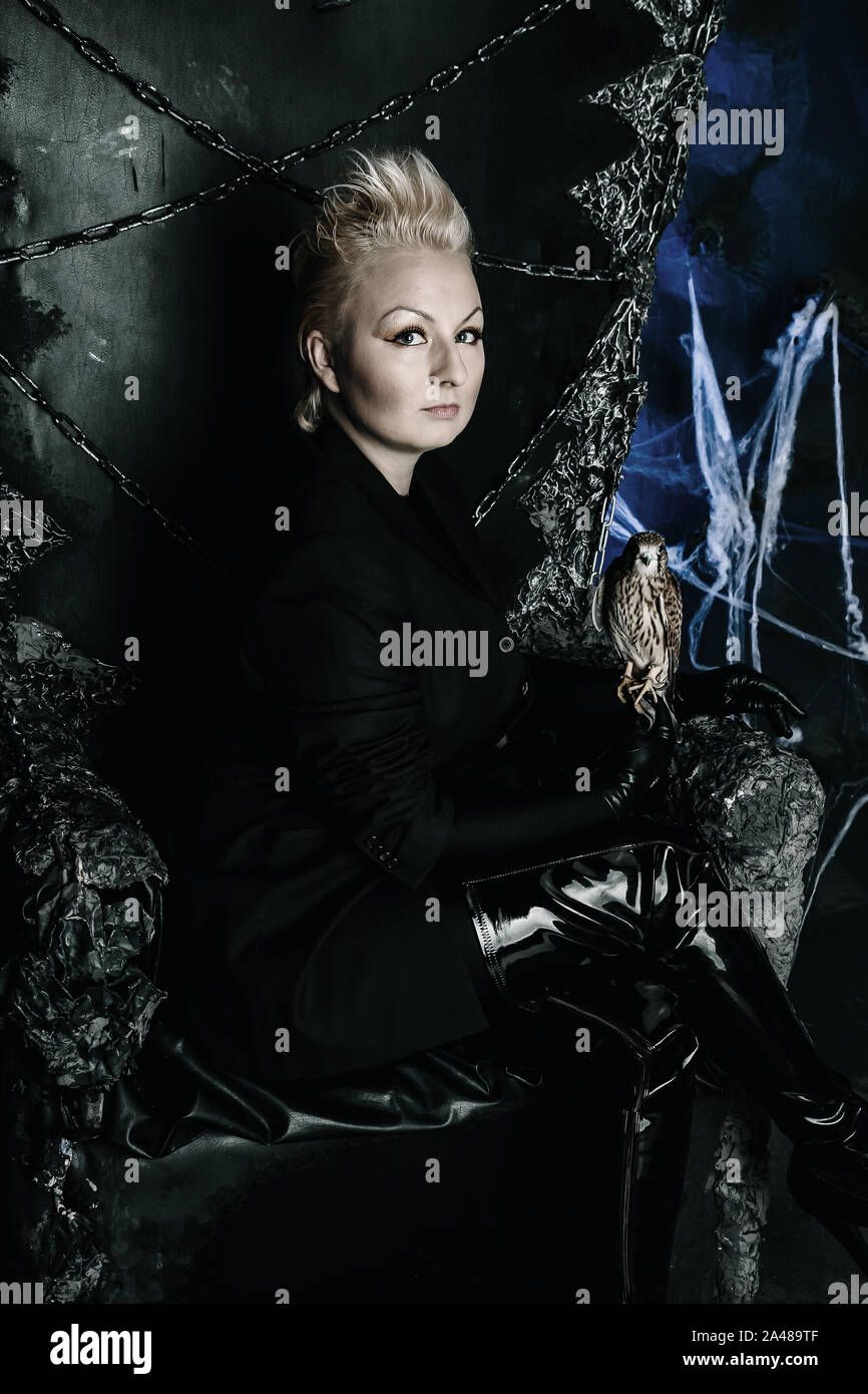 Photo of a female witch queen holding bird and sitting on a gothic ...