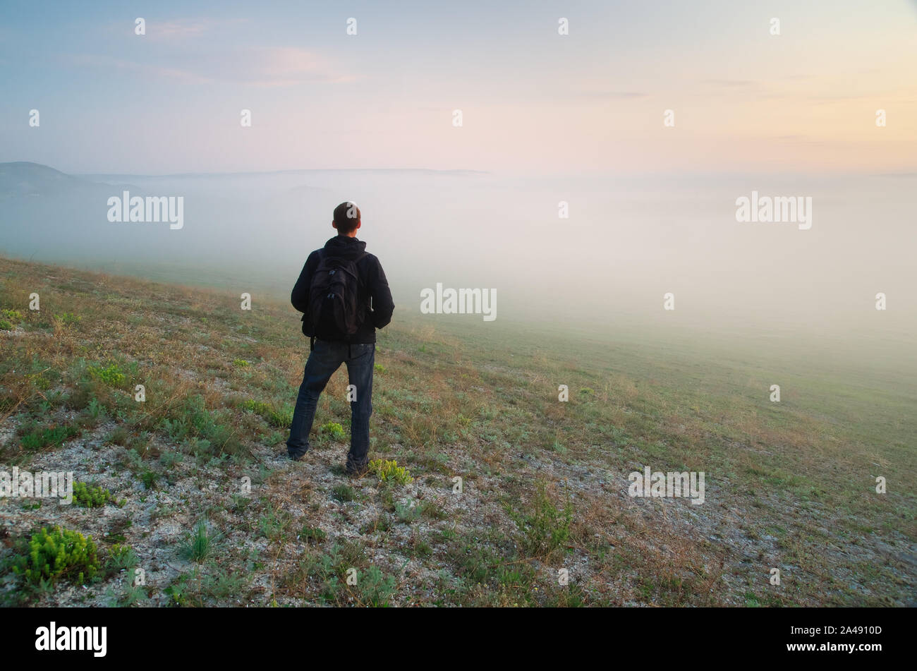 Man standing in fog meadow Stock Photo - Alamy
