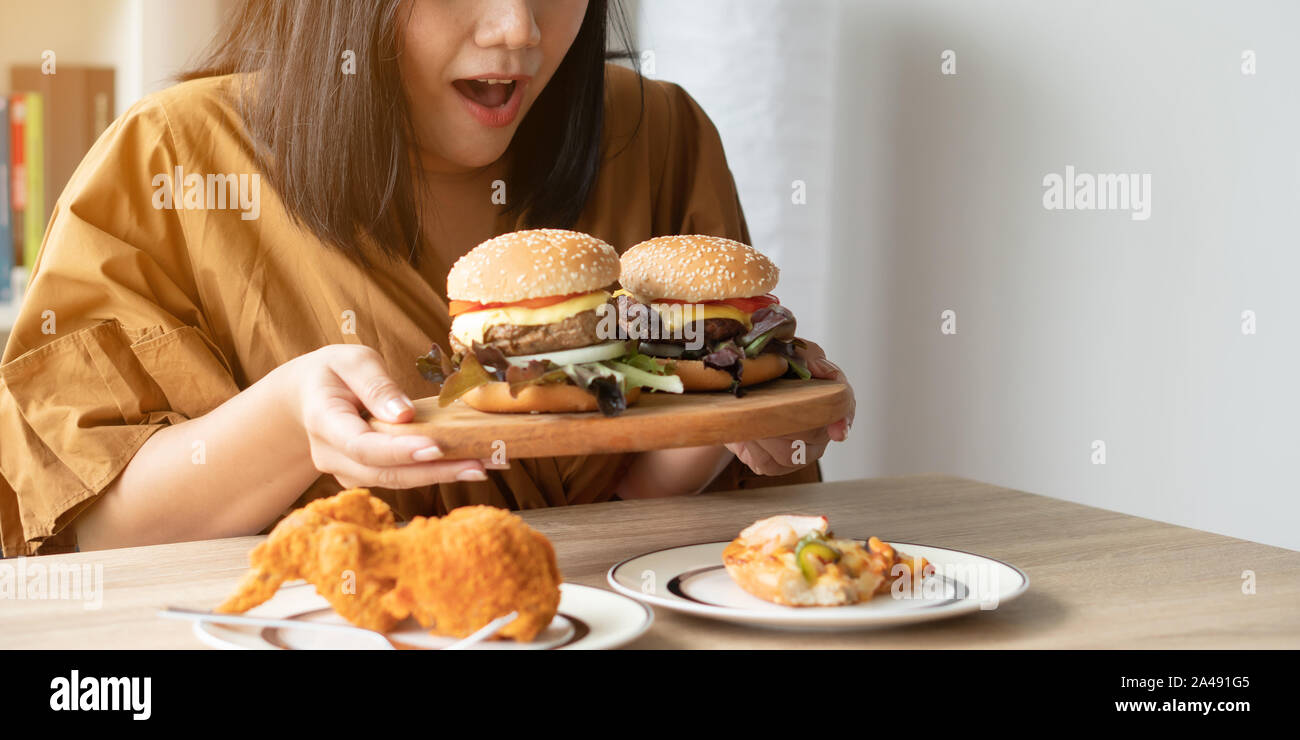 Hungry overweight woman holding hamburger on wooden plate, Fried ...