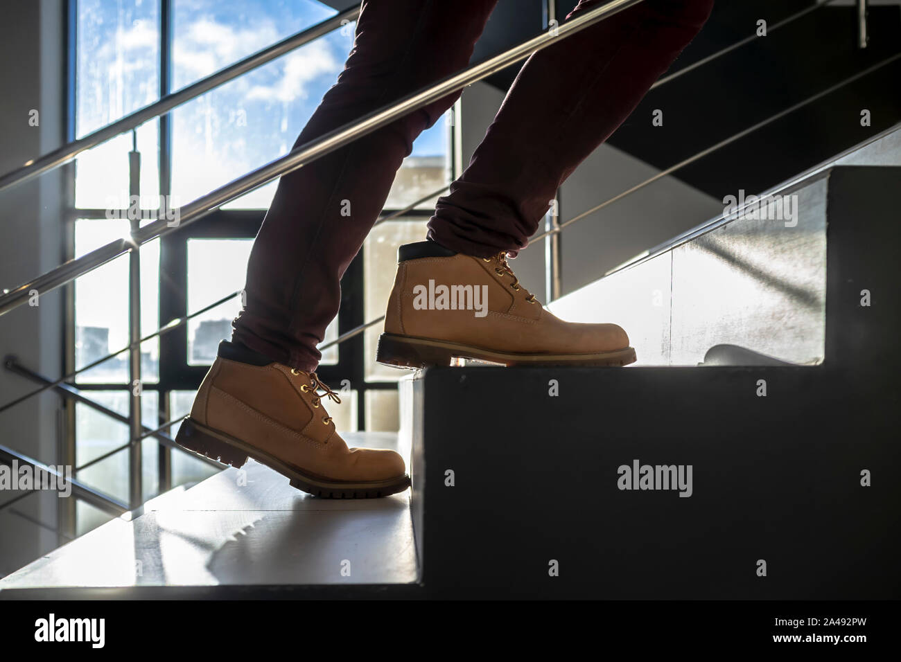 bottom view of a young man walking up the stairs with metal railings ...