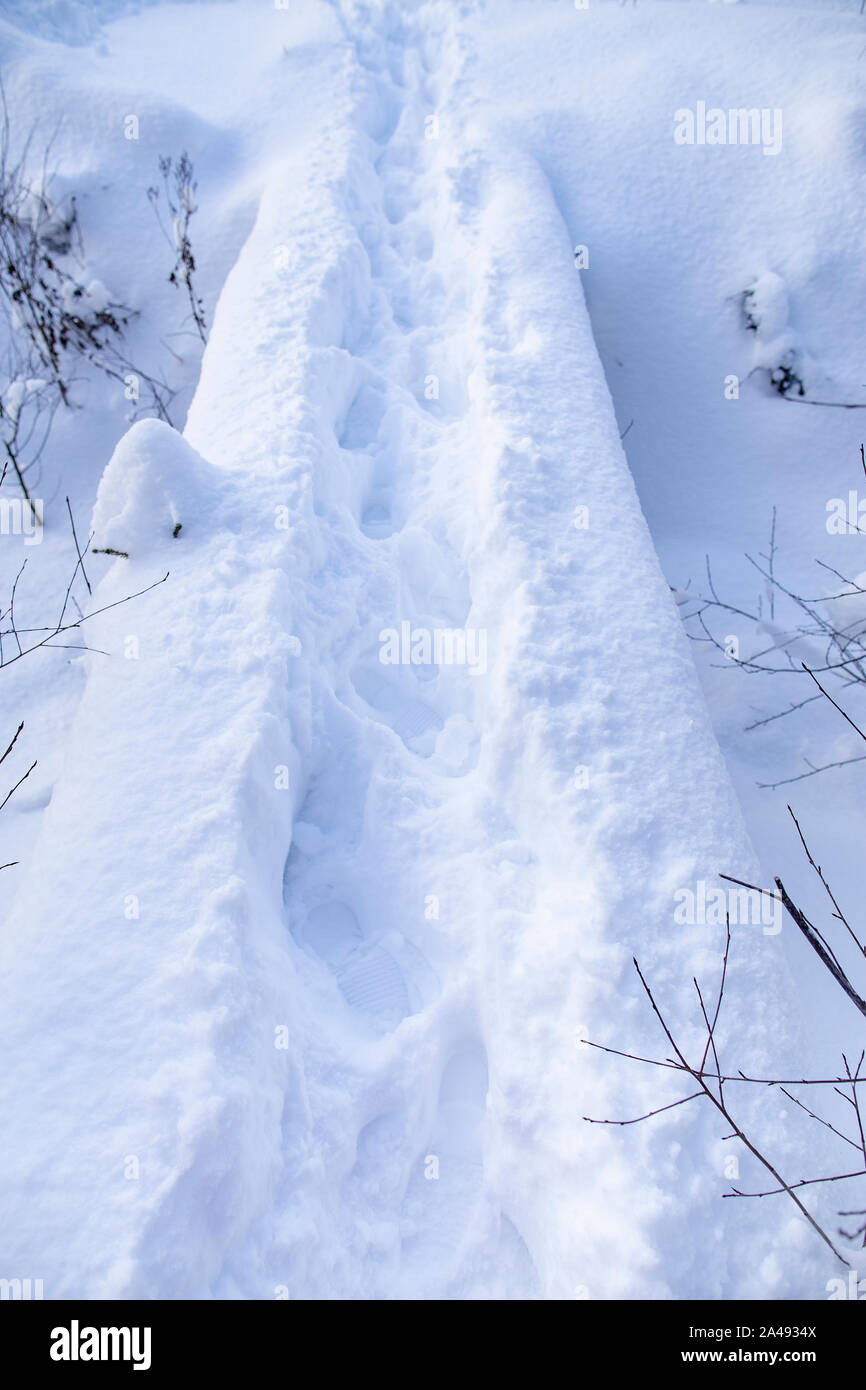 A small, narrow bridge with a path trampled down in deep snowdrifts ...