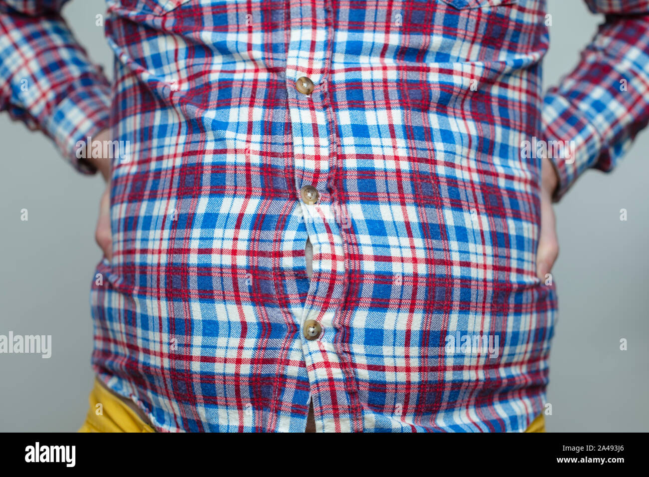 fat man in a plaid shirt is having trouble fastening his small clothes ...