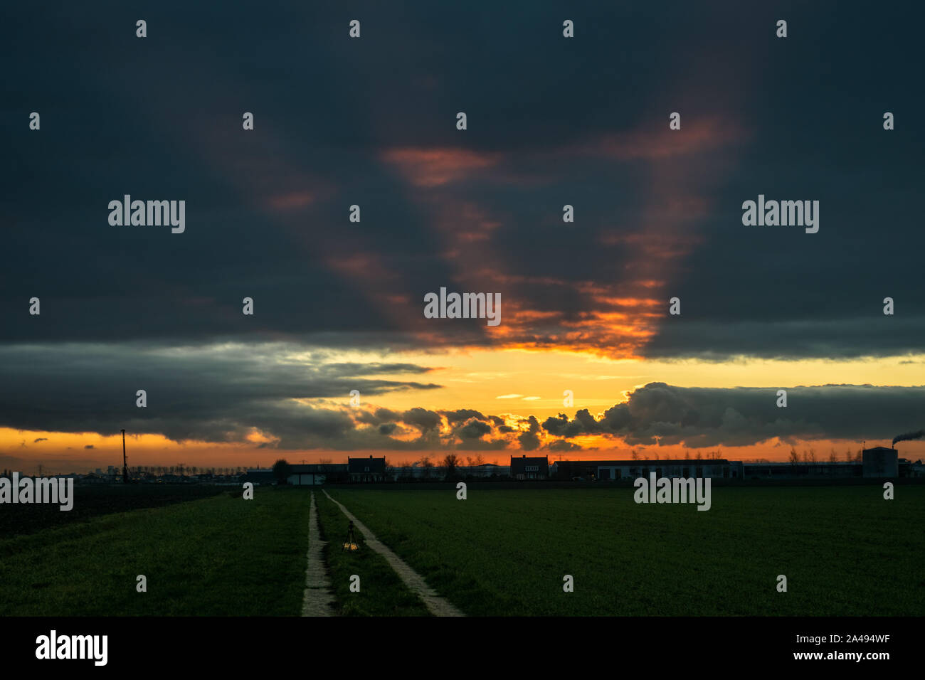 Sun rays shine at the bottom of the clouds after sunset. A path is ...