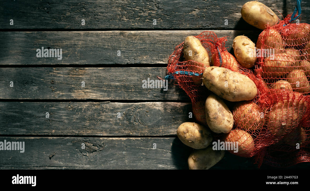 Potatoes crop in a bag on a wooden garden table background with copy ...