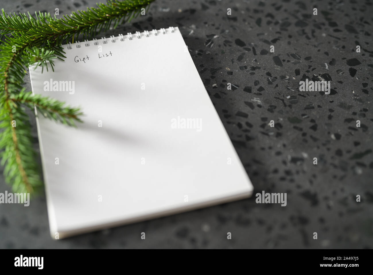 Notepad with gift list and spruce twig on terrazzo countertop, shallow ...