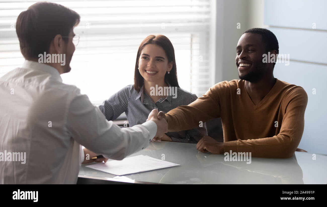 Smiling african american satisfied client shaking hands with salesman ...