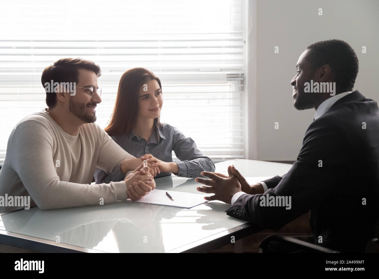 Smiling african american male banker consulting young married couple ...