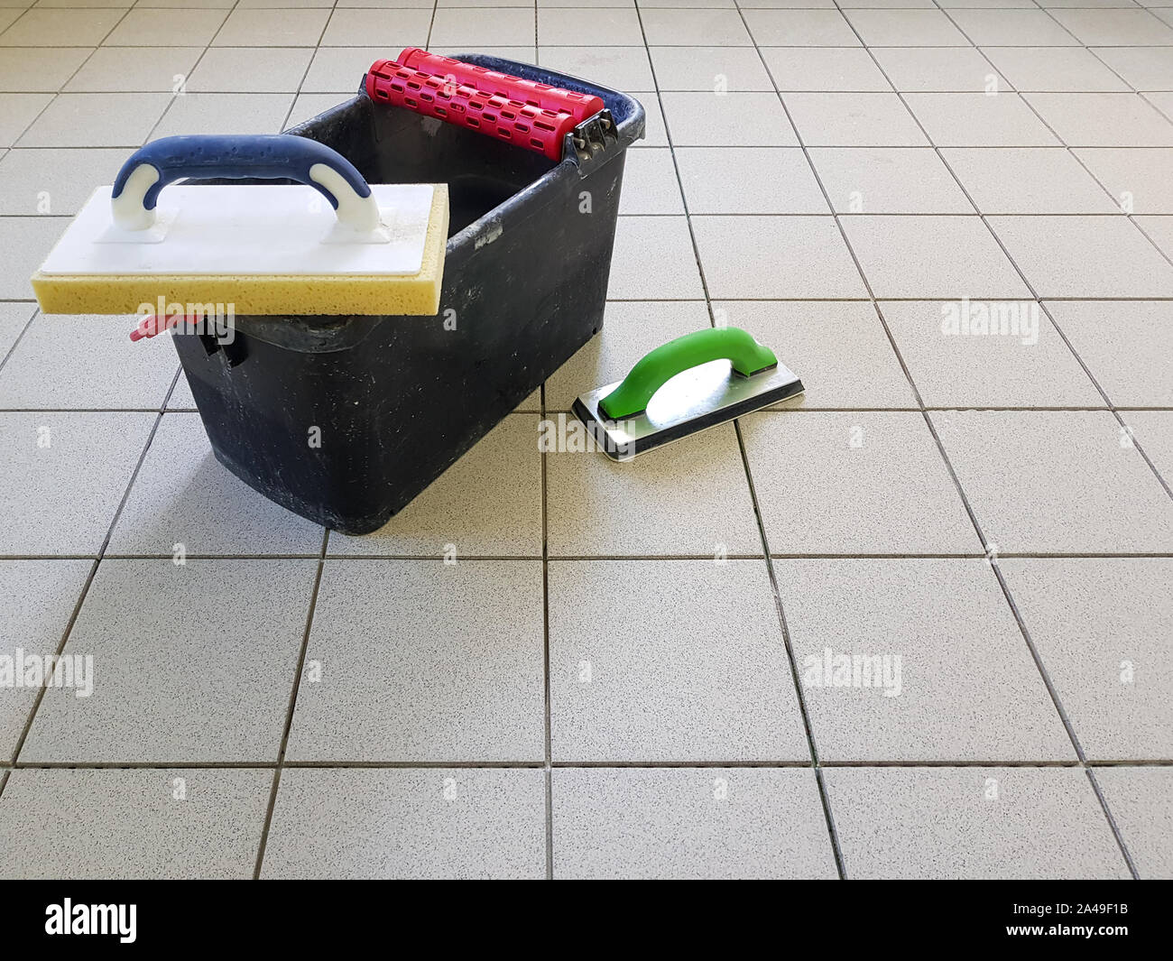 Tools for grouting ceramic tiles. Tilers using a rubber trowel and ...