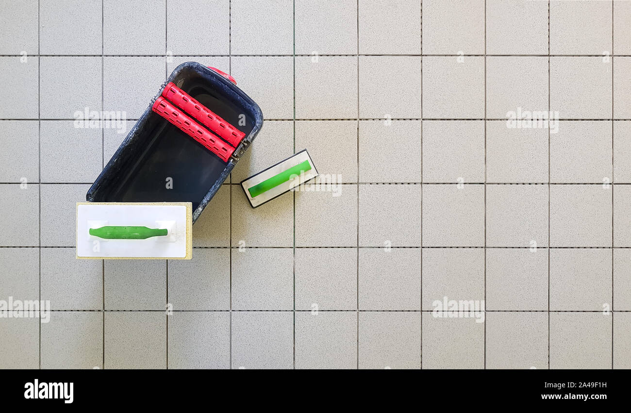 Top view of tools for grouting ceramic tiles. Tilers using a rubber ...