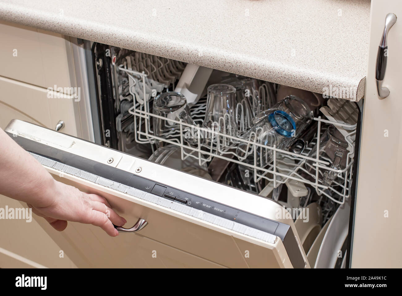 Female hand opens the dishwasher, in which perfectly clean dishes after ...