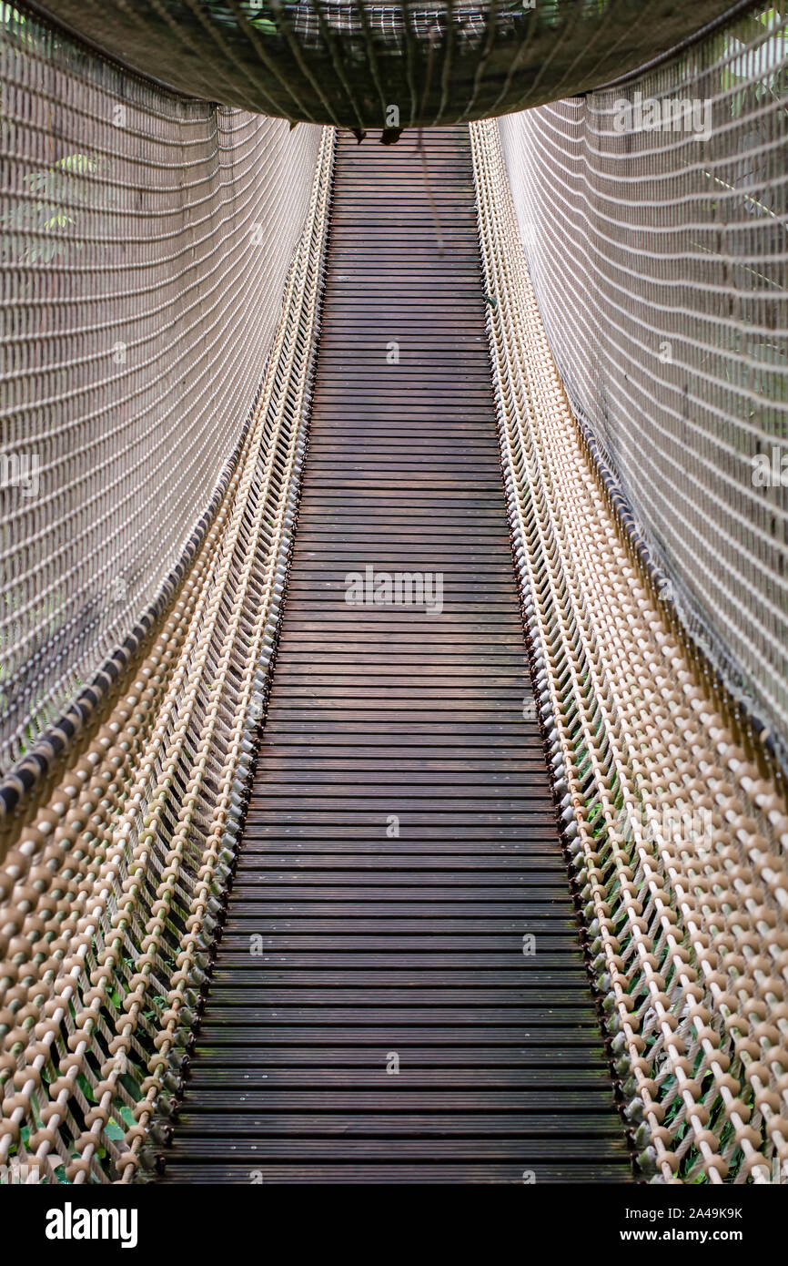 Suspended wooden bridge with ropes and mesh on the sides and top for ...