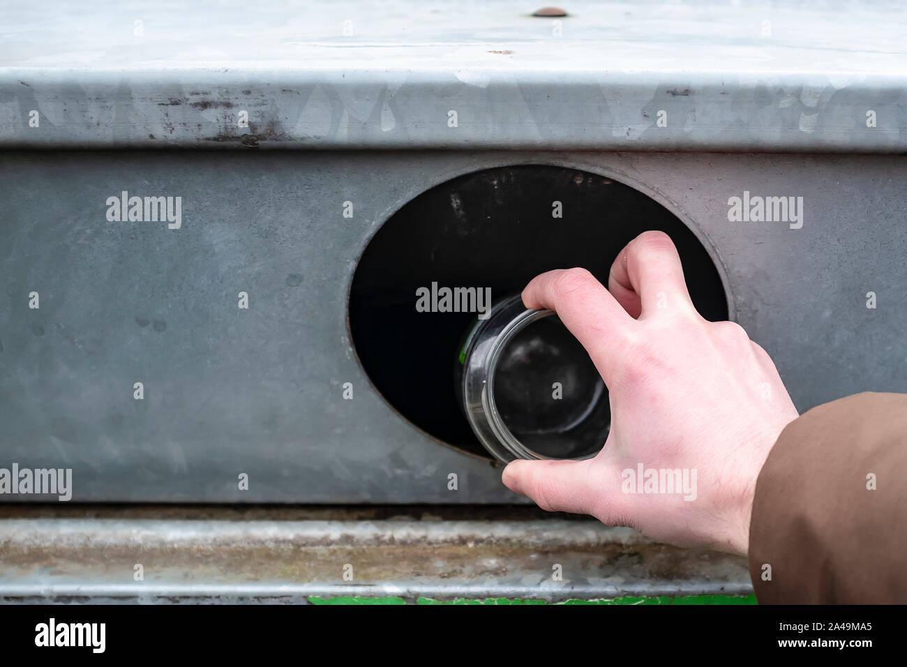 Human hand throws used white cans of canned baby food into a container ...